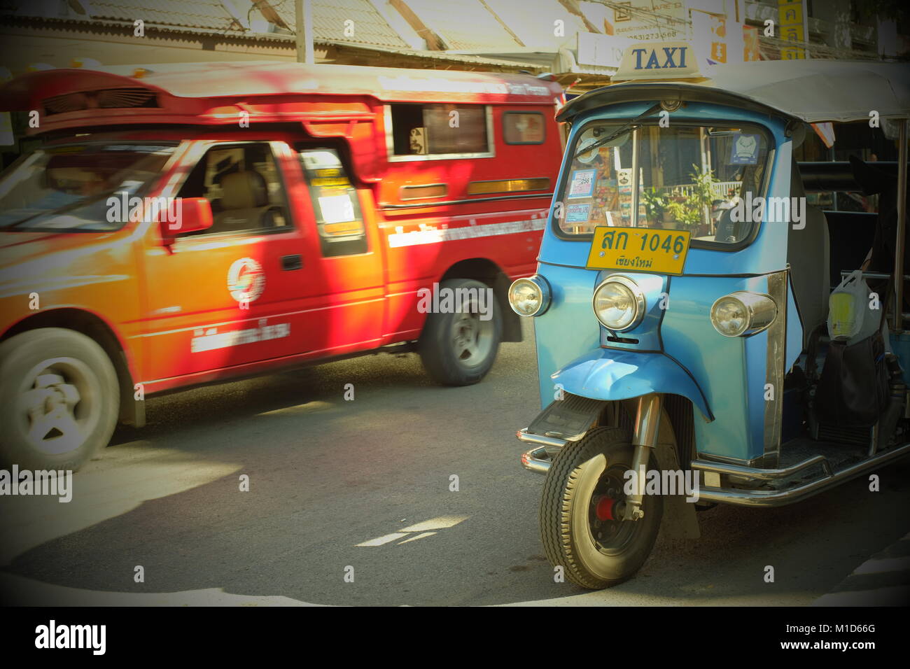 A blue tuk-tuk and a red songthaew taxi in Chiang Mai, Thailand. 24-Jan ...