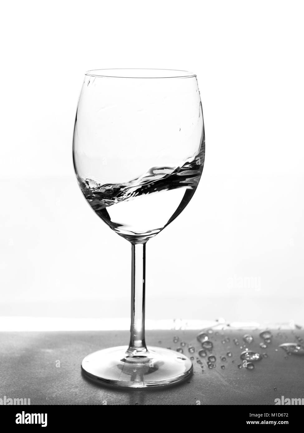Half empty glass with water splashes in motion on white background ...