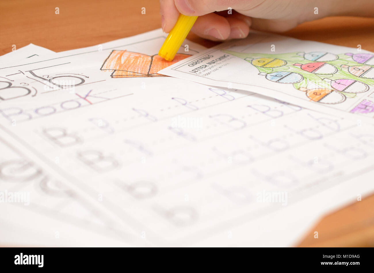 A child's hand writes and displays English letters in a notebook and ...