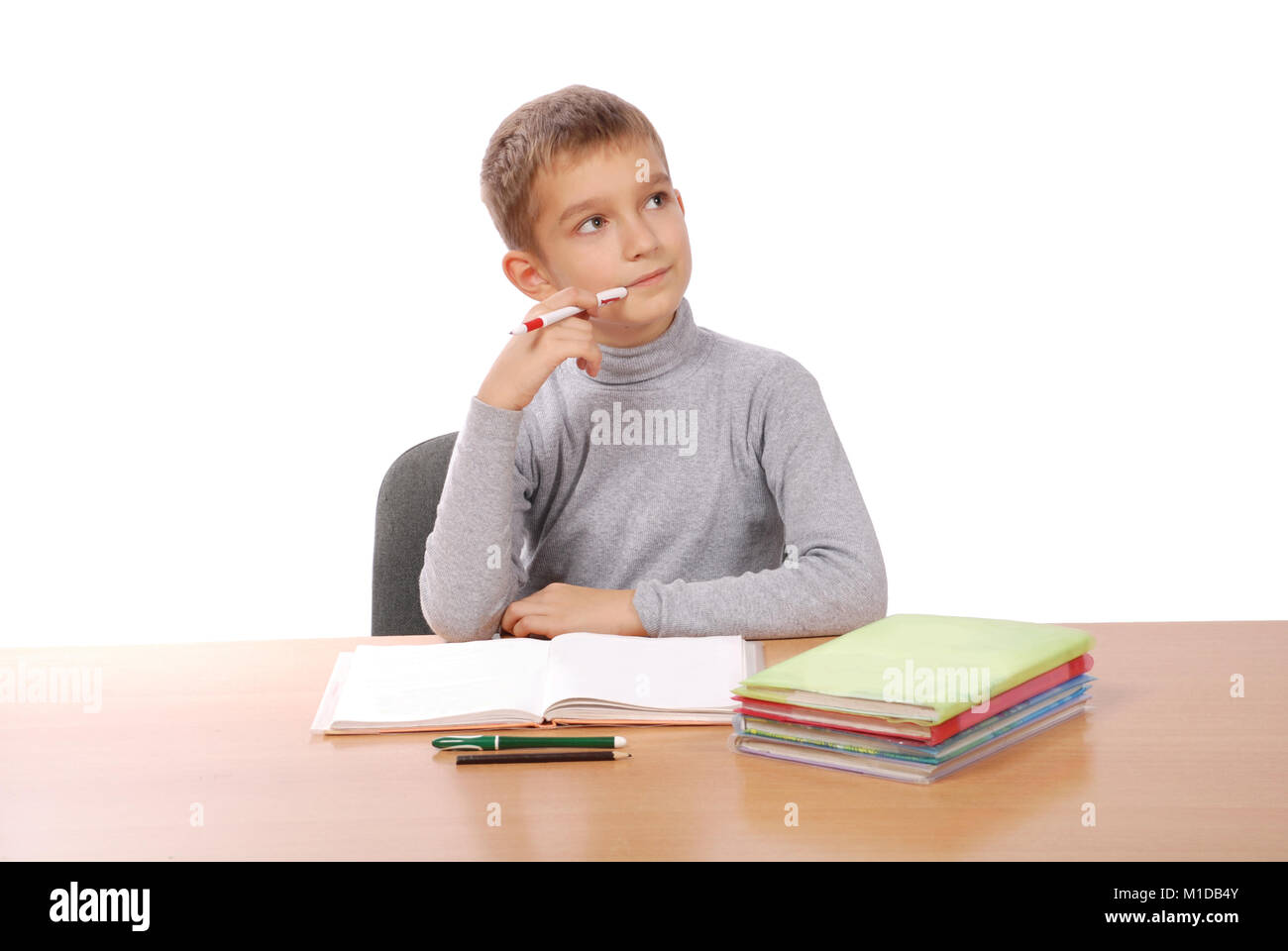 The boy behind a table dreams on white background Stock Photo - Alamy
