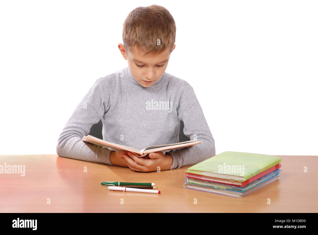 boy behind a table reads the book on white bacground Stock Photo - Alamy