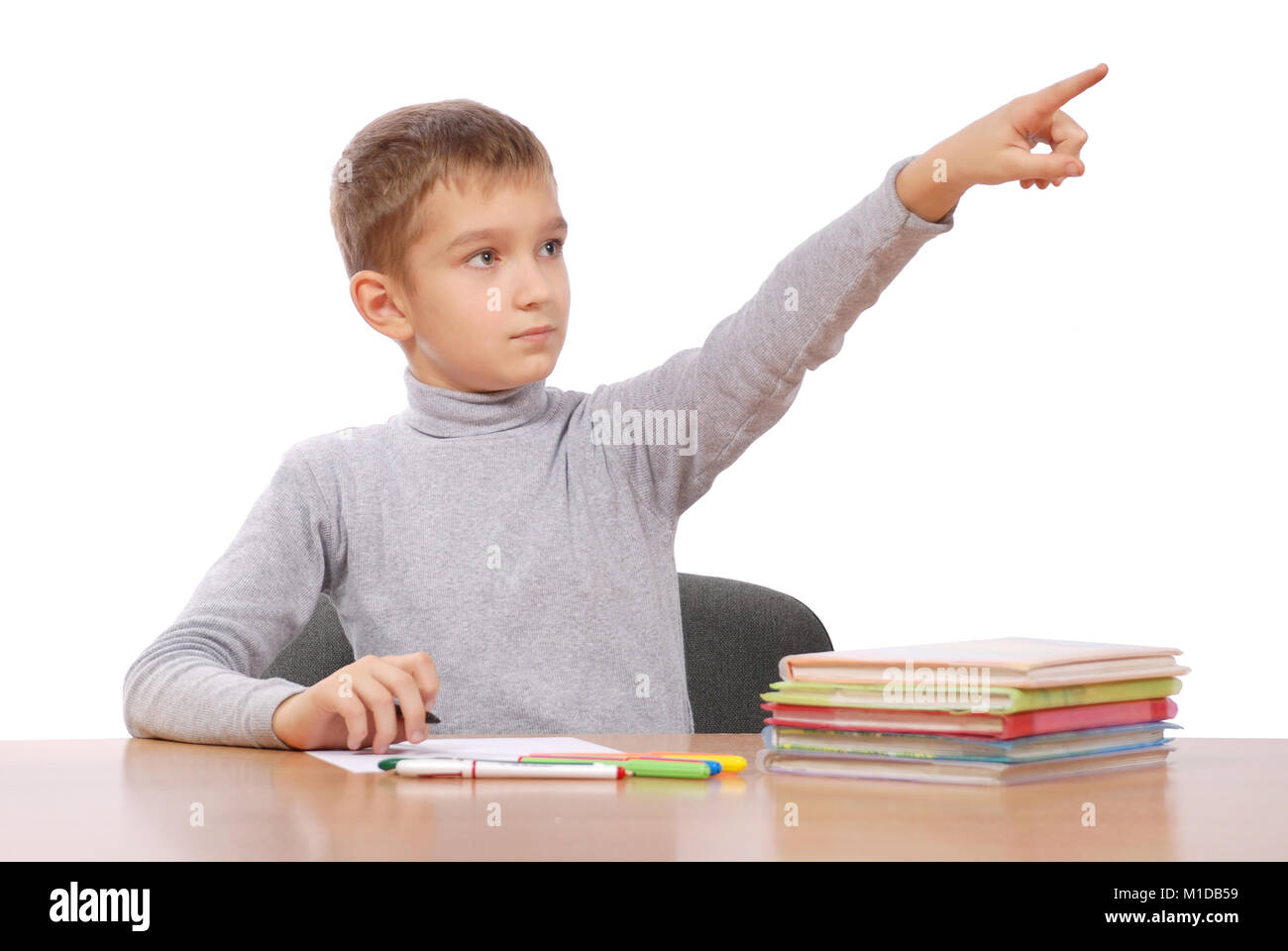 boy sits at a table. boy shows a finger on a subject on white ...