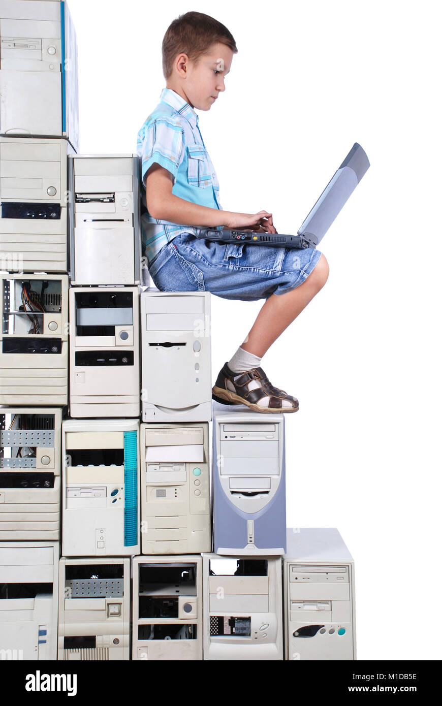 boy plays with laptop a steps from old computers on white background ...