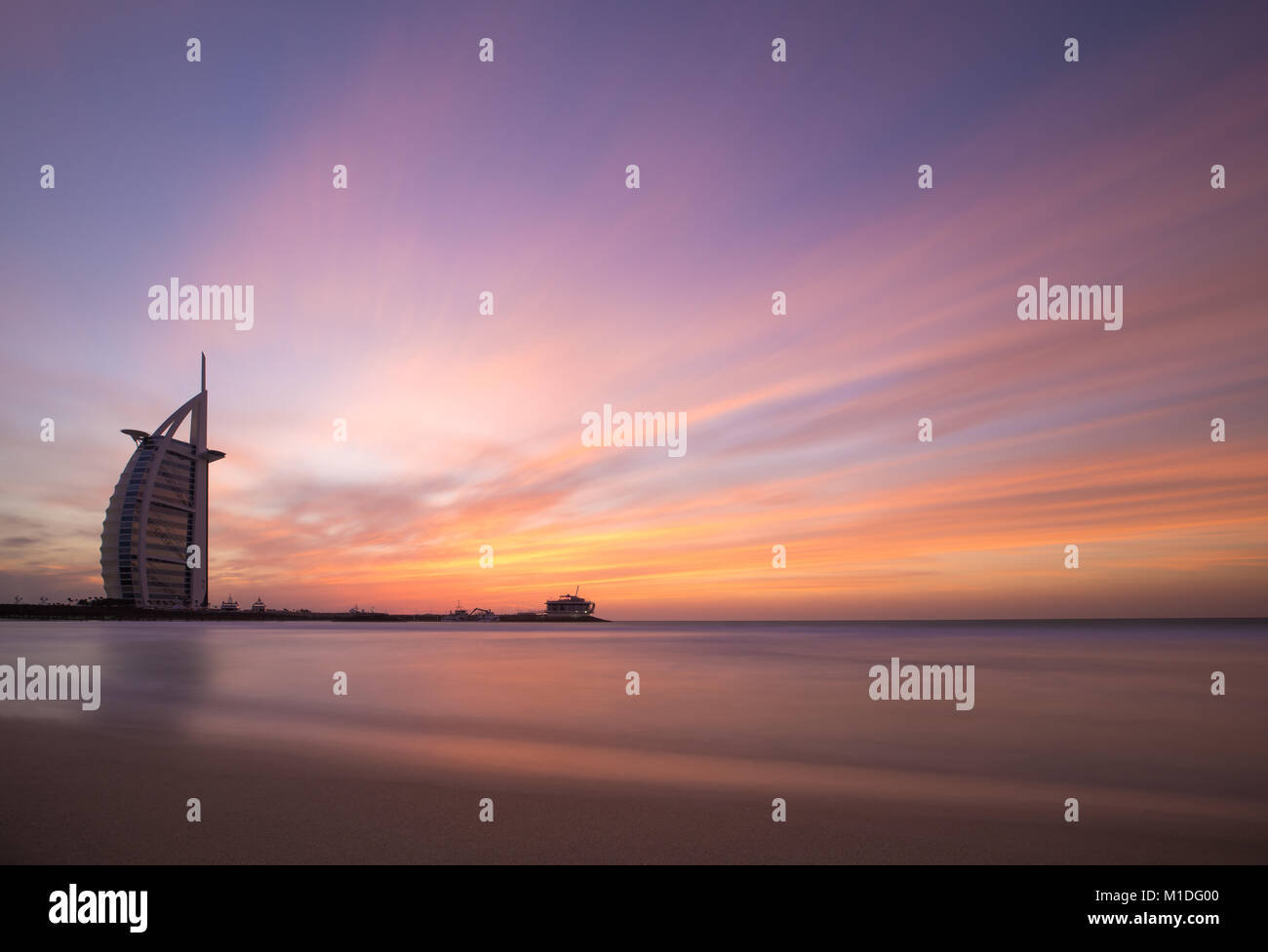 Dubai skyline during a colorful sunset as viewed from the public beach ...