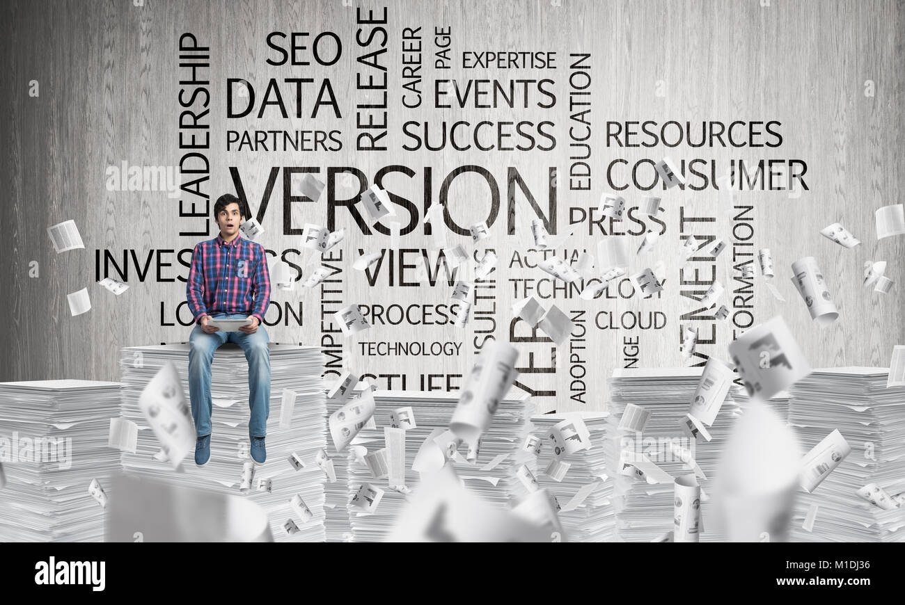 Attractive man sitting on pile of paper documents Stock Photo - Alamy