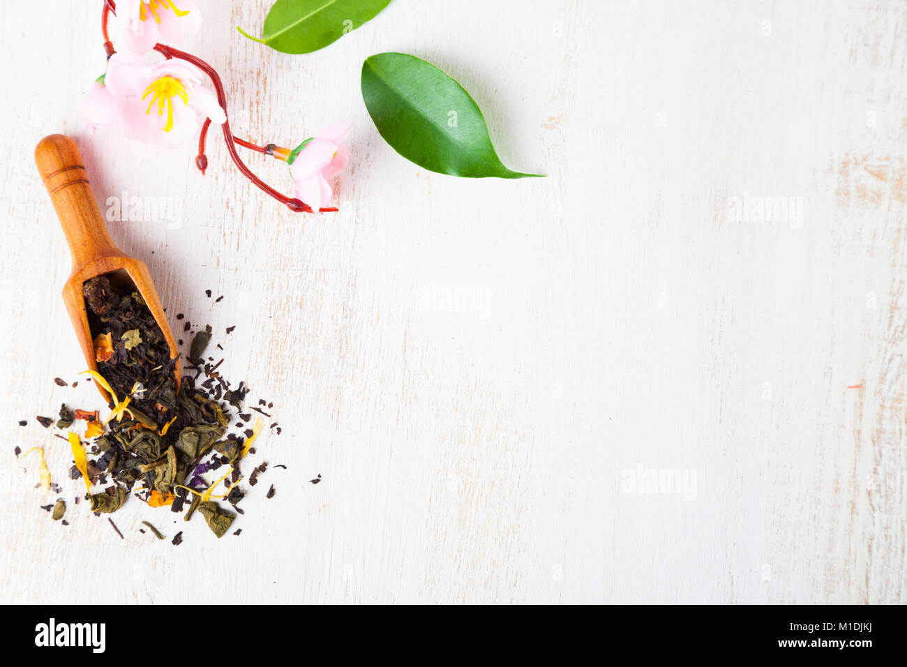 Black tea with flower petals, tea leaves and sakura on a wooden ...