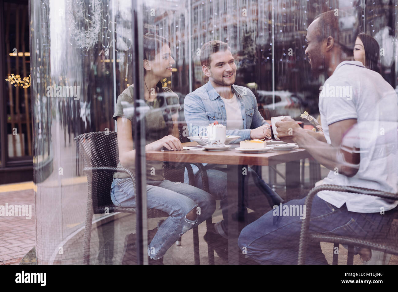Excited four friends exchanging opinion Stock Photo - Alamy