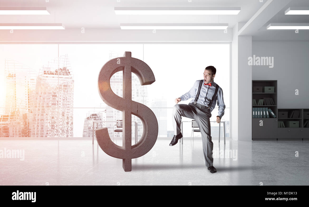Determined banker man in modern office interior breaking dollar figure ...