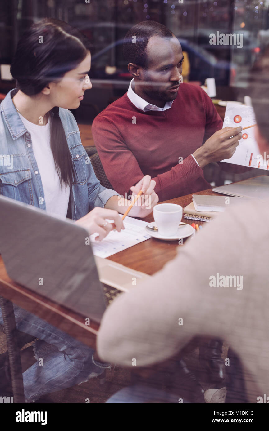 Musing three colleagues compiling statistics Stock Photo - Alamy
