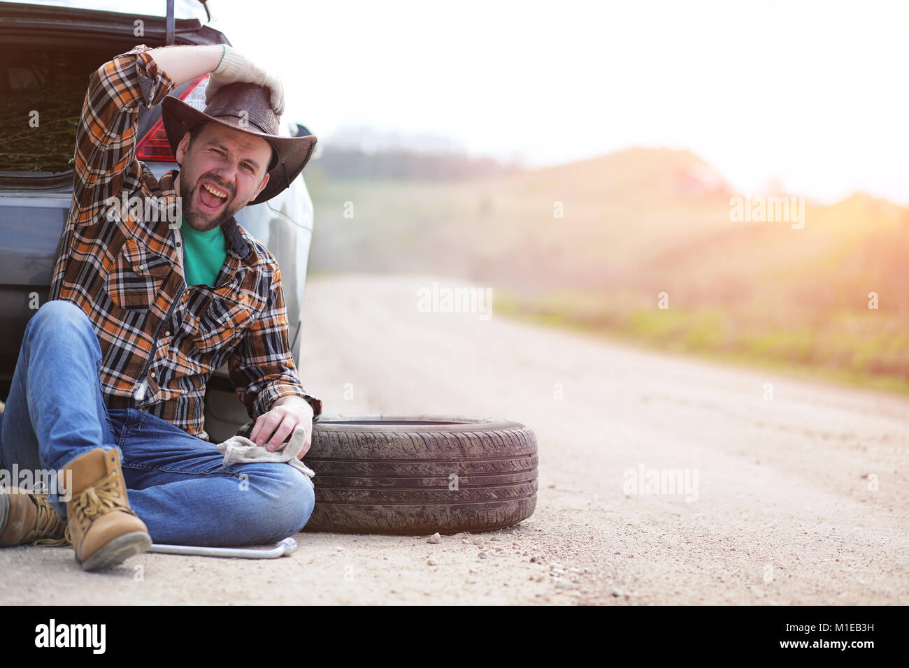 Man is sitting on the road by the car Stock Photo - Alamy
