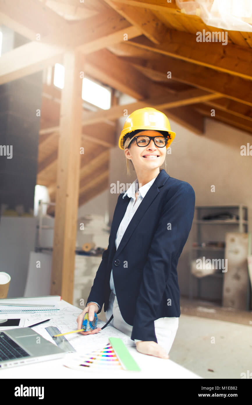 very pretty young female architect wearing yellow helmet is planning a ...