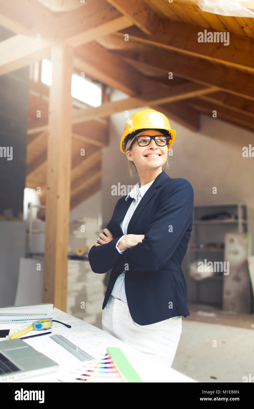 very pretty young female architect wearing yellow helmet is planning a loft in a house Stock ...