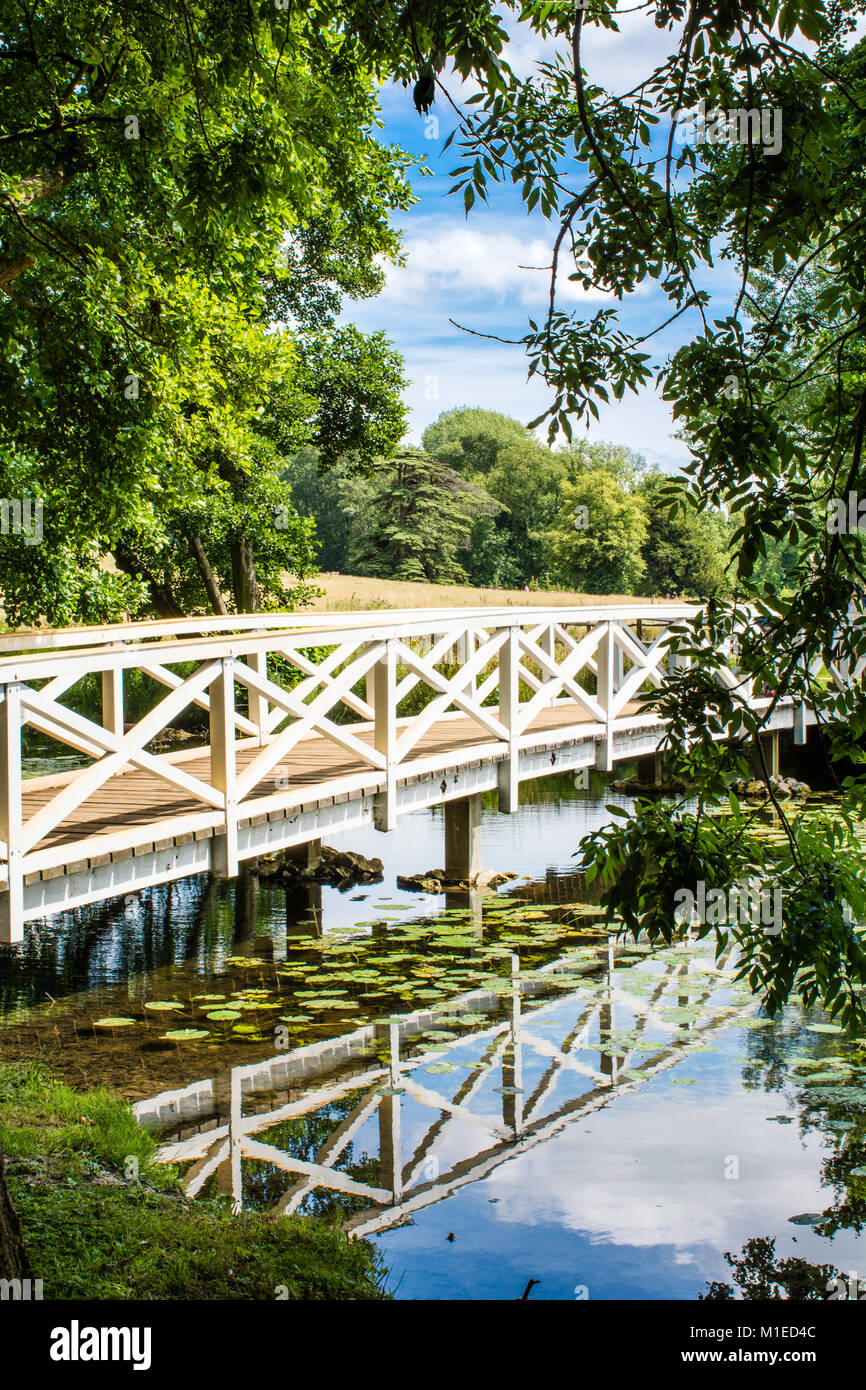 A wooden foot bridge across water from woodland to open fields ...