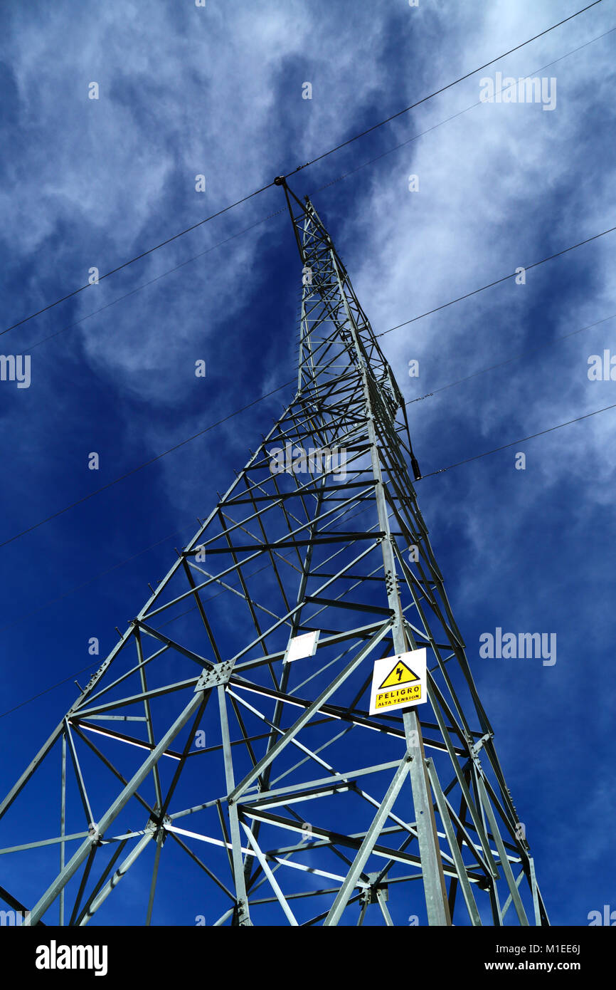 Peligro / Danger sign in Spanish on electricity pylon against blue sky ...
