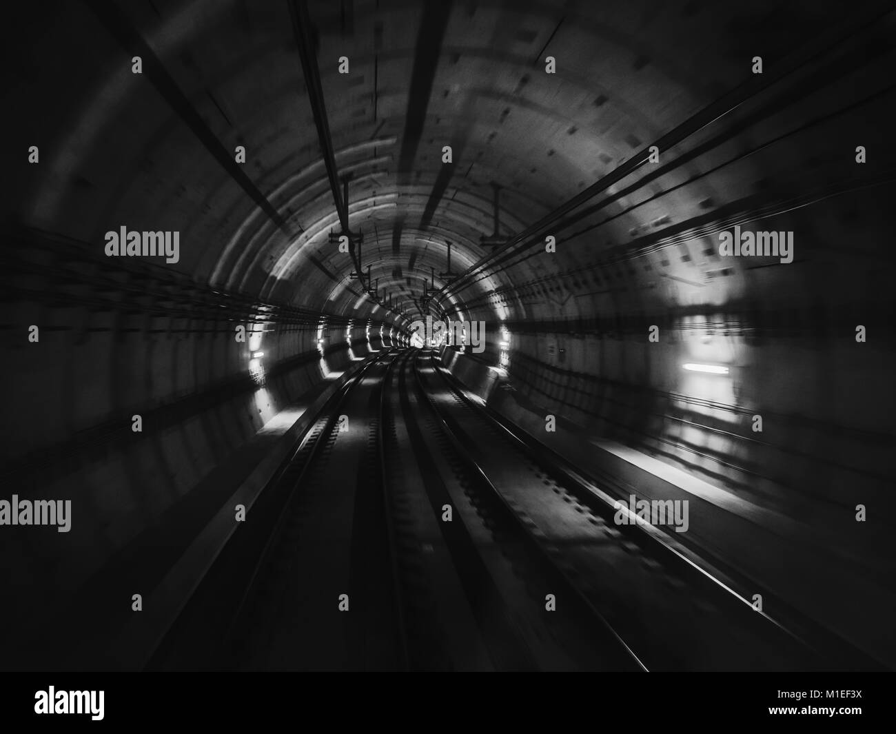 View of a subway tunnel from the front of a moving train. Fast underground train gaining speed ...