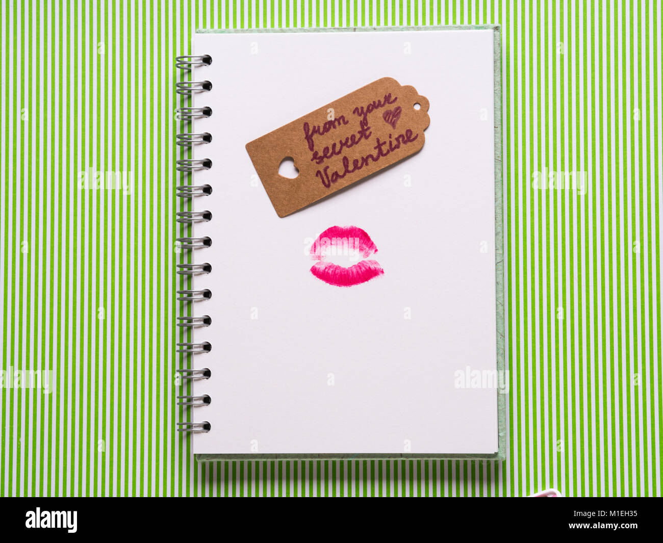 White page with girlish pen and lipstick kiss on green background ...
