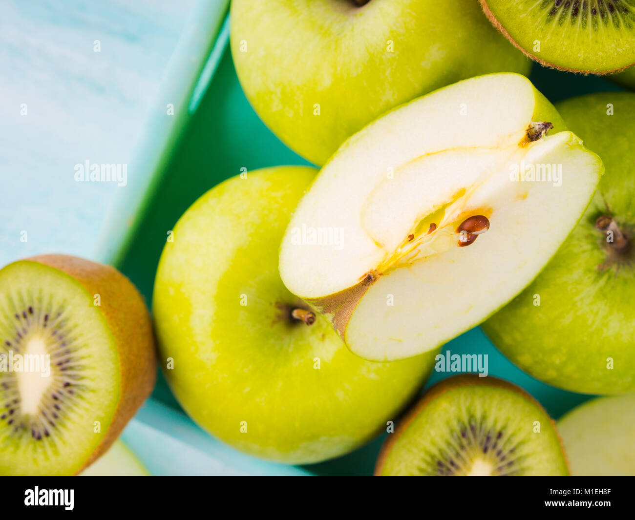 Green apples and kiwi on turquoise background Stock Photo - Alamy