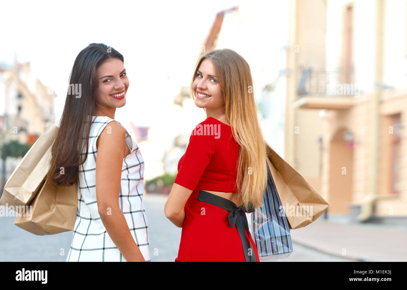 Back view of beautiful girls with shopping bags doing shopping in the ...