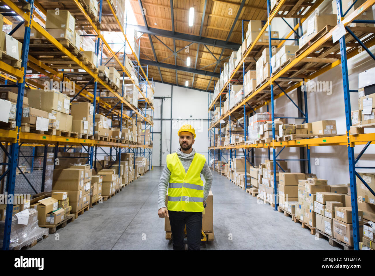 Male warehouse worker pulling a pallet truck Stock Photo - Alamy