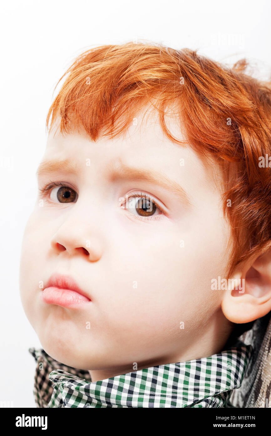 little boy in red hair with a frustrated facial expression, close-up on ...