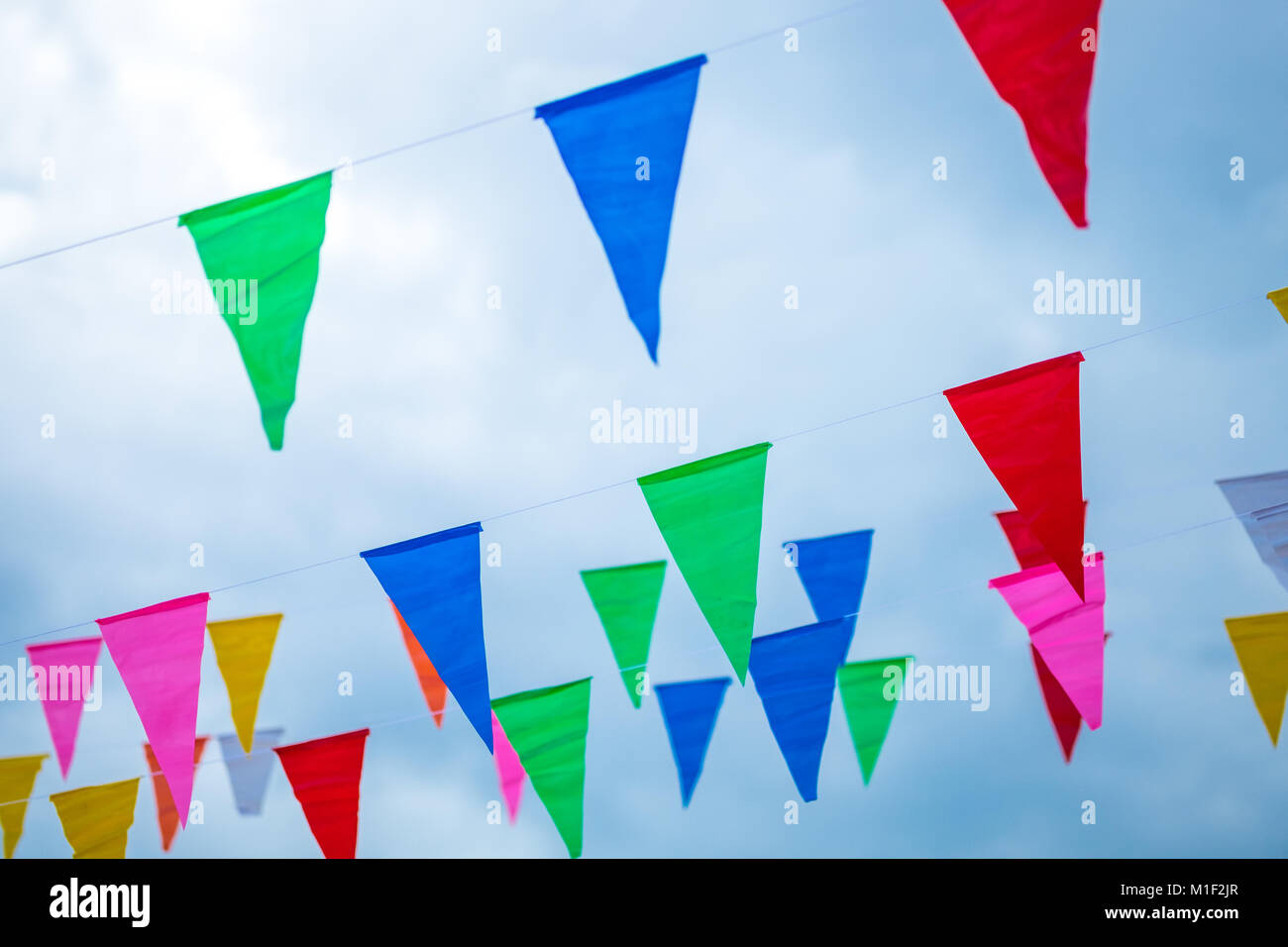 Colorful small flags paper made hanging on the rope with blue sky ...