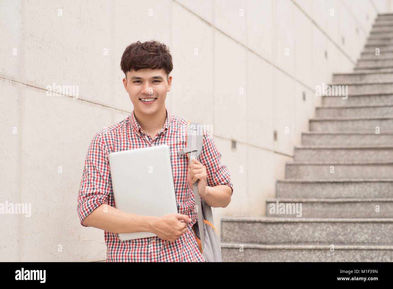 College asian male student holding laptop in campus Stock Photo - Alamy