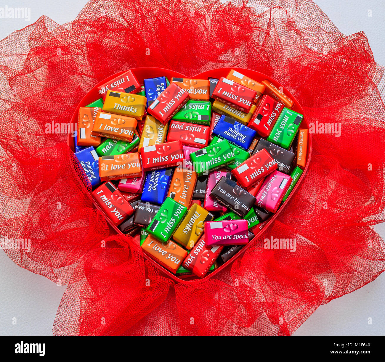 A lot of chocolates with love messages in red heart-shaped box lined ...