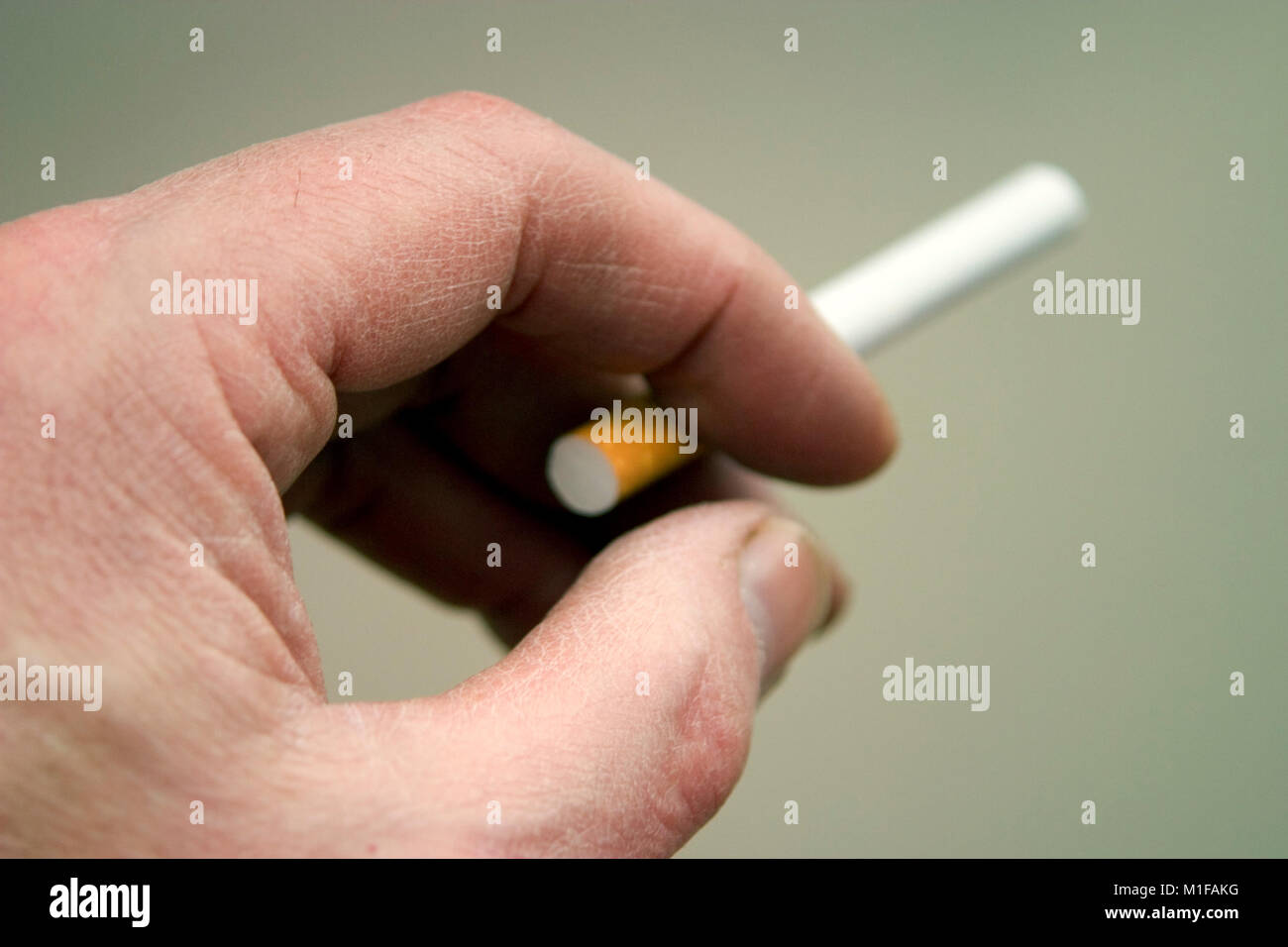 A mans hand holding an unlit cigarette Stock Photo - Alamy