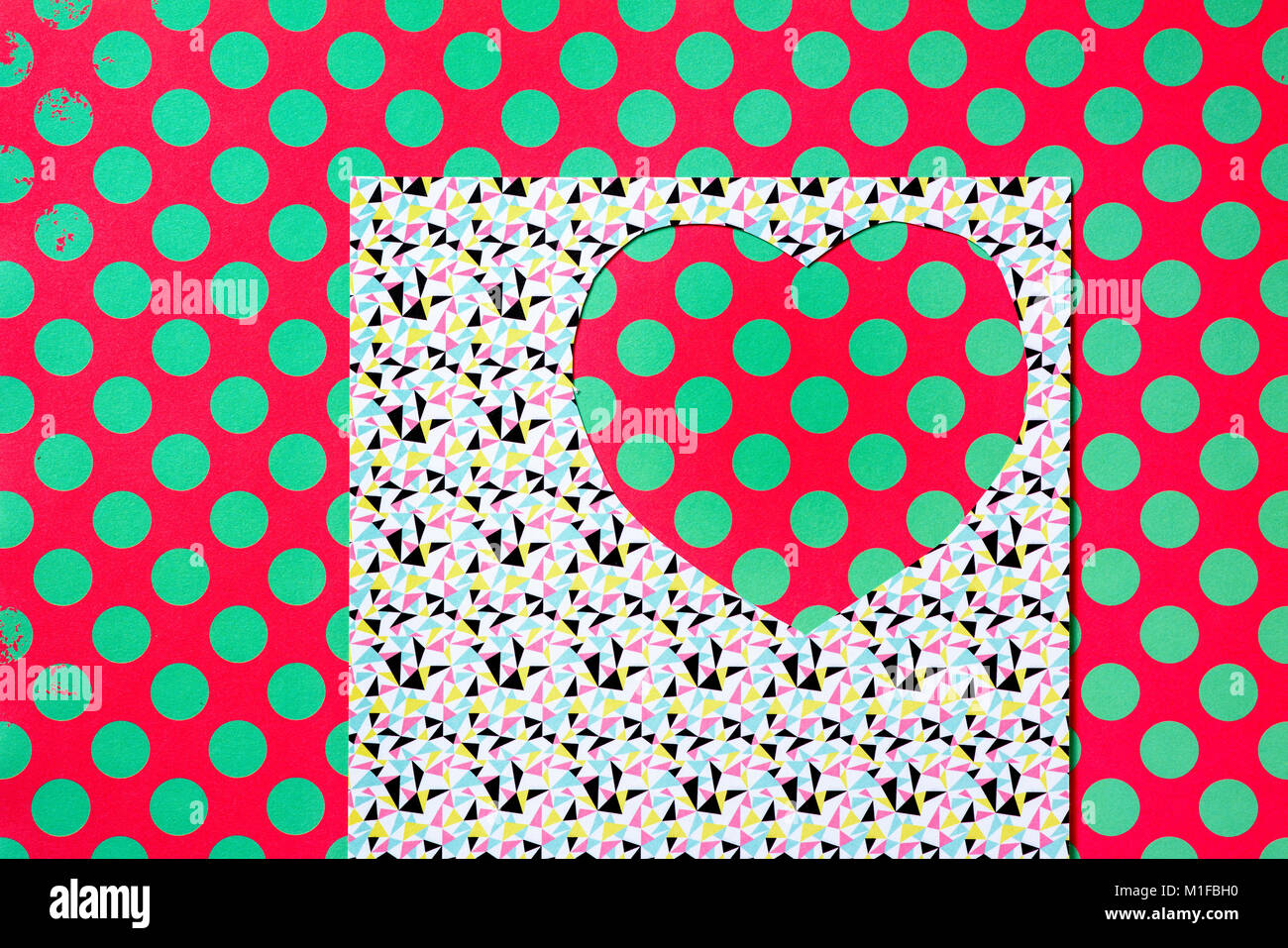 a heart cut out on a colorful abstract-patterned paper, and a red ...