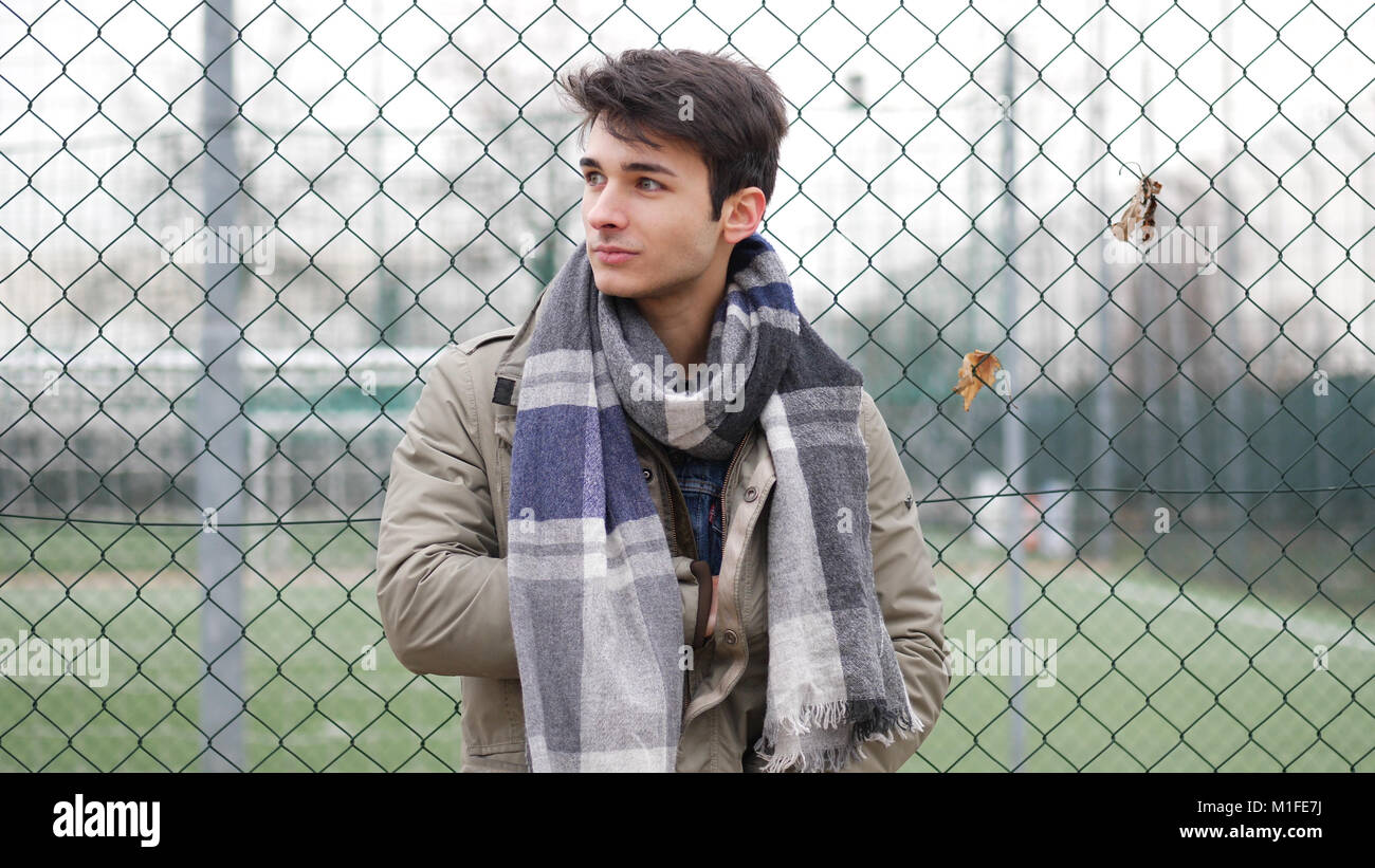 Young handsome man in scarf posing at metal grid Stock Photo - Alamy