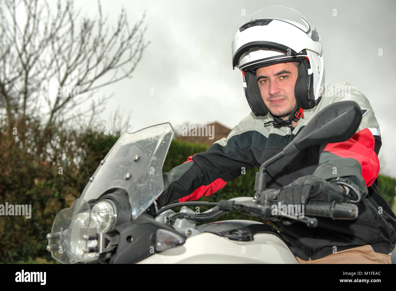 young man sits on a motorcycle and has helmet on his head Stock Photo ...