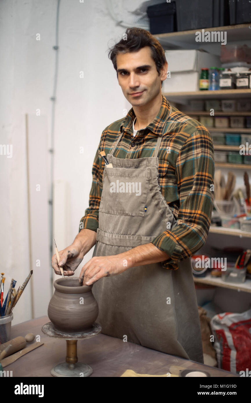 Young man making and decorating pottery in workshop Stock Photo - Alamy