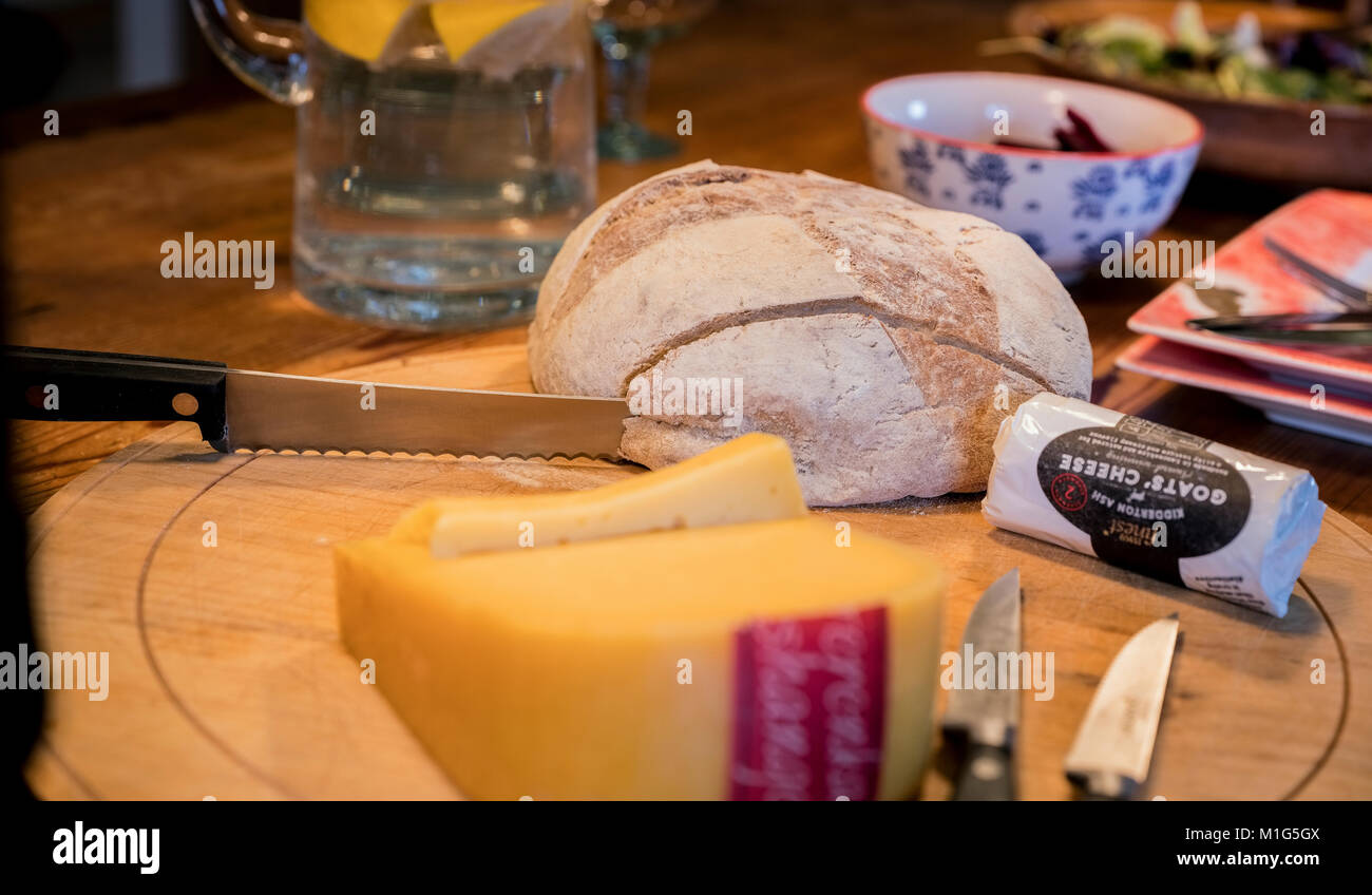 A farmhouse kitchen table set for a lunch of bread, cheese and salad ...