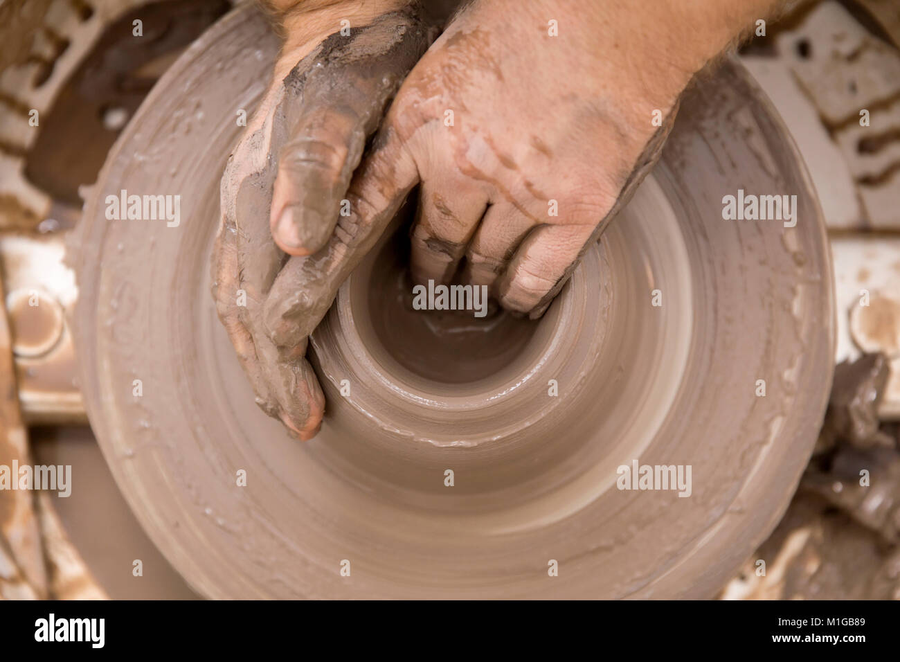 Close up detail view at an artist makes clay pottery on a spin wheel ...