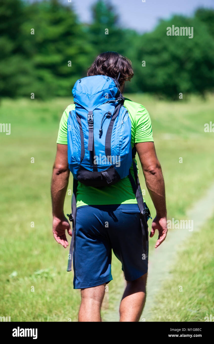 Back view at young man with backpack hiking at green nature Stock Photo ...