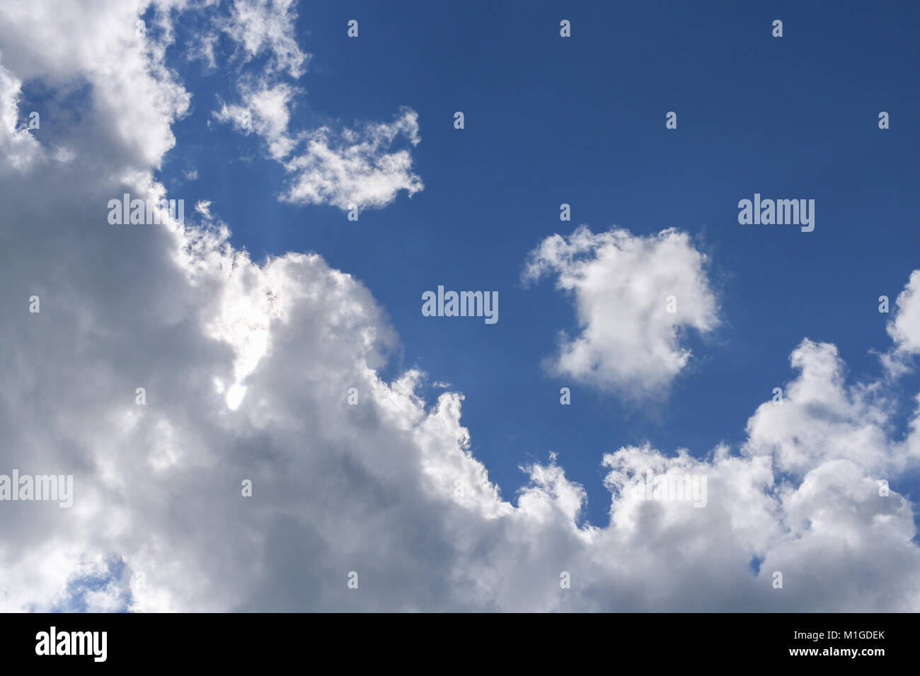 A large cumulus cloud and a small white cloud, separated from it on a ...