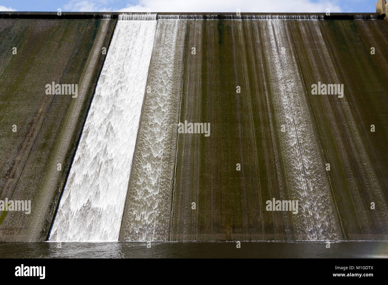 White water overspill run off on the stark sunlit concrete wall of Llys ...