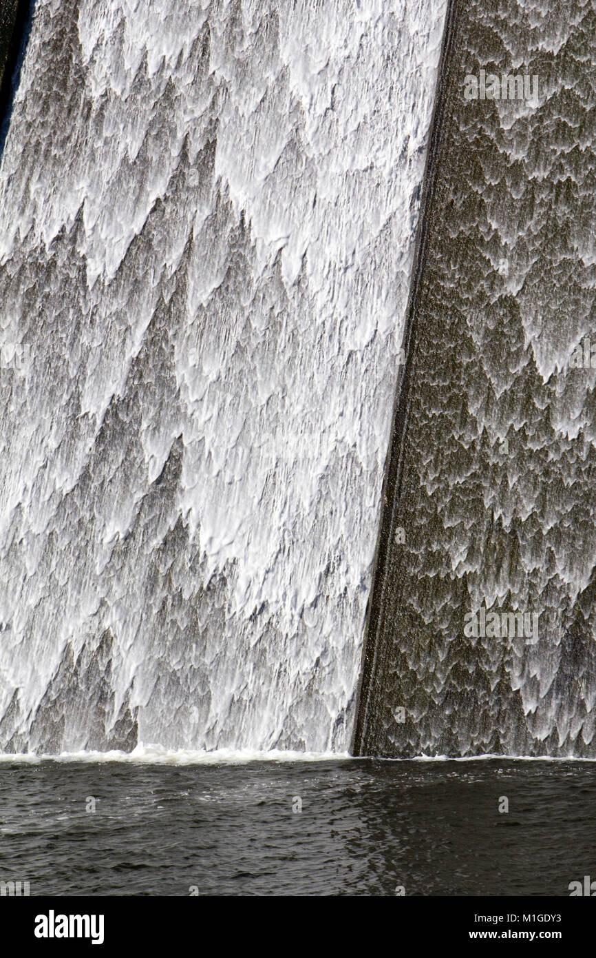 White water overspill run off on the stark sunlit concrete wall of Llys ...