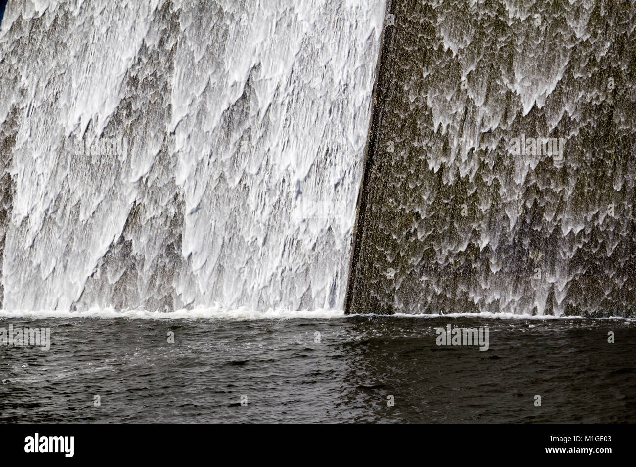 White water overspill run off on the stark sunlit concrete wall of Llys ...