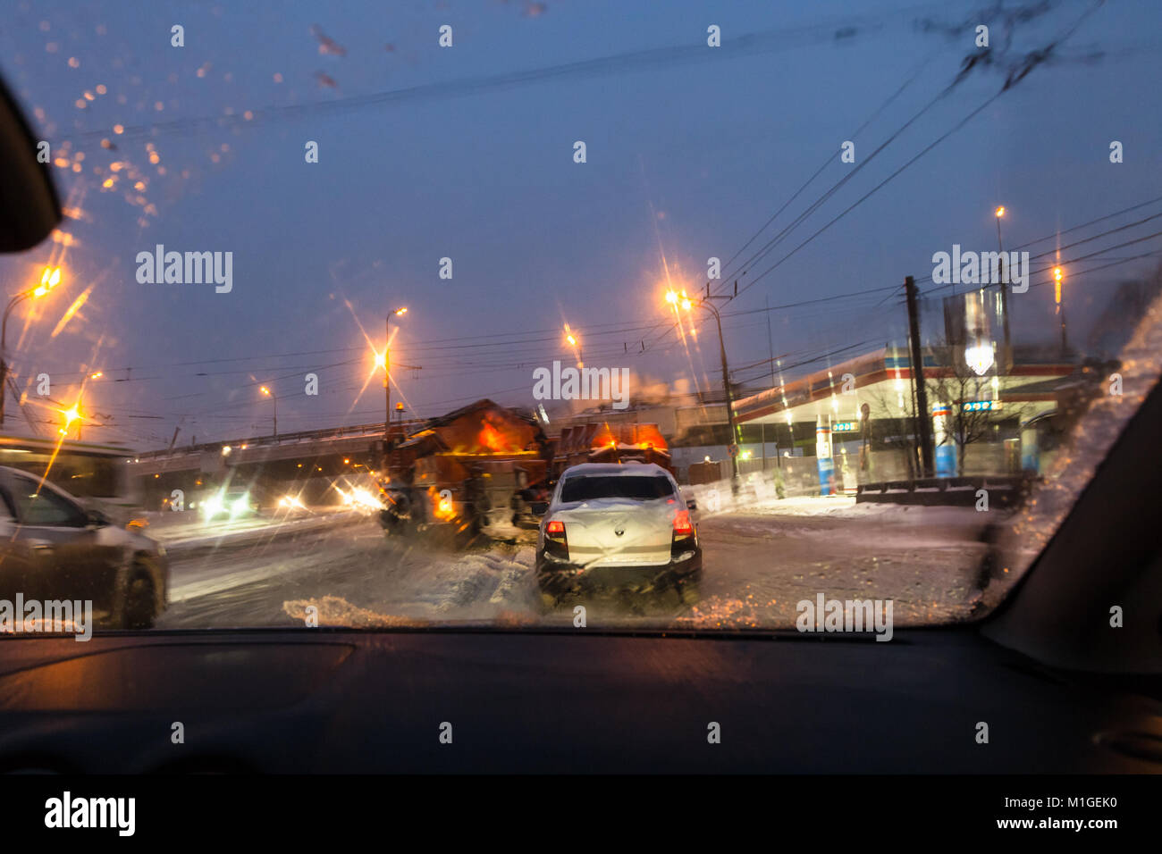view of car traffic and street sweeping machines through wet windscreen ...