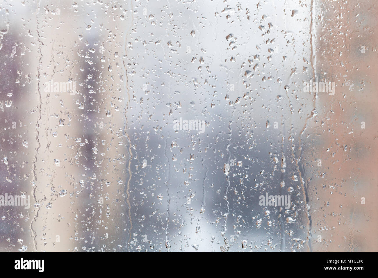 urban background - rain drops on window glass (focus on water trickles ...