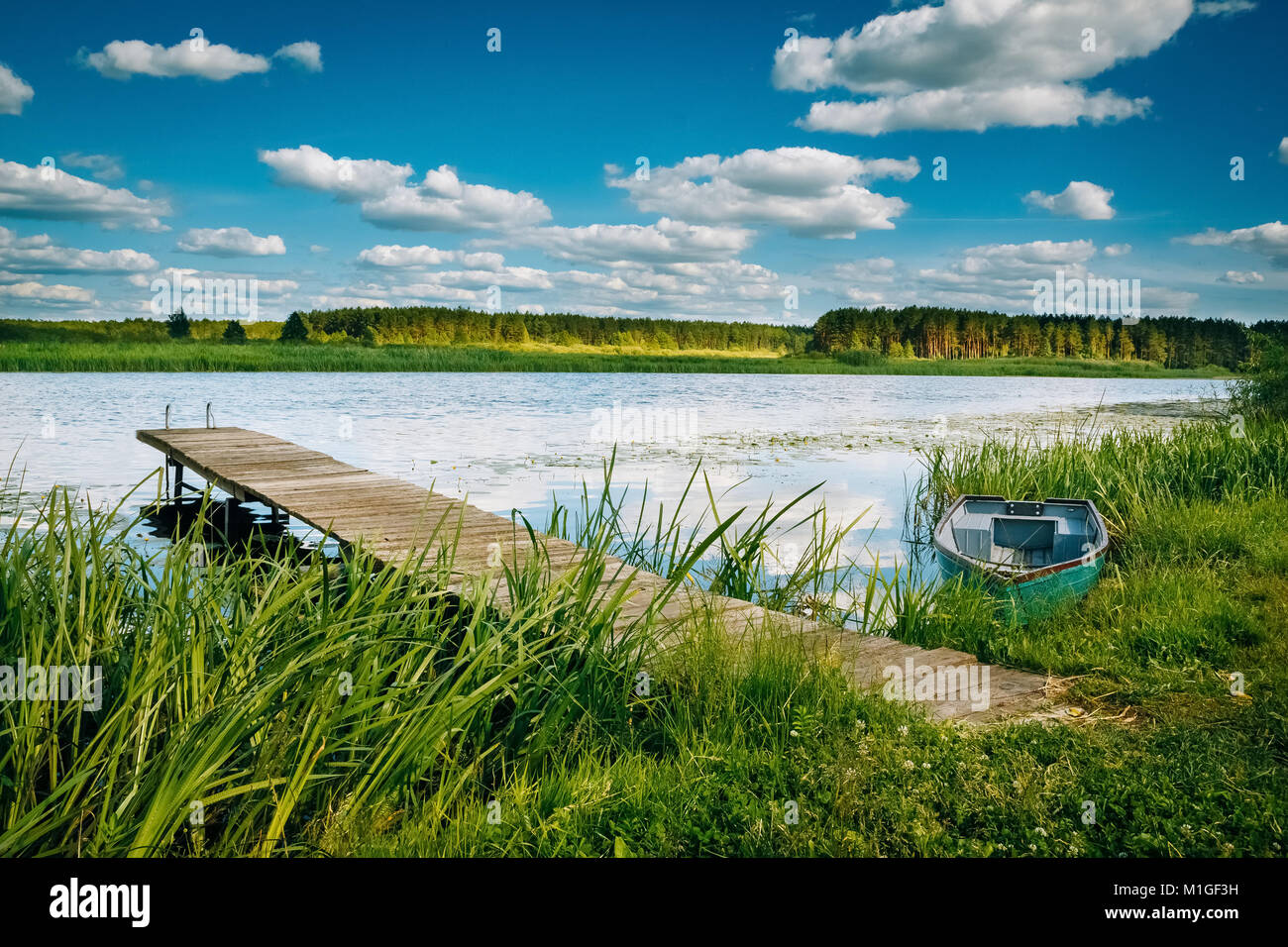 Beautiful river landscape with an old wooden pier and a fishing boat ...