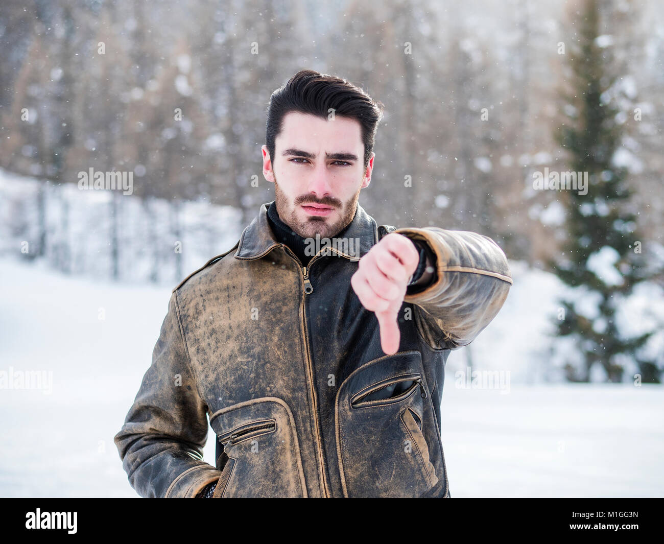 Handsome young man doing thumb down sign with two hands, outside in ...