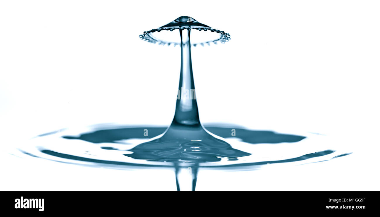 Splash and crown on rippled blue liquid or water surface . Water splash ...