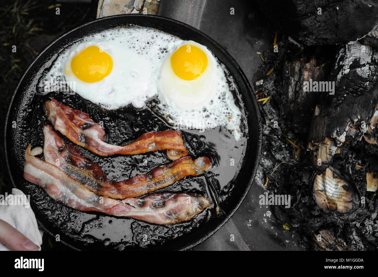 Bacon and eggs cooking over a campfire Stock Photo - Alamy