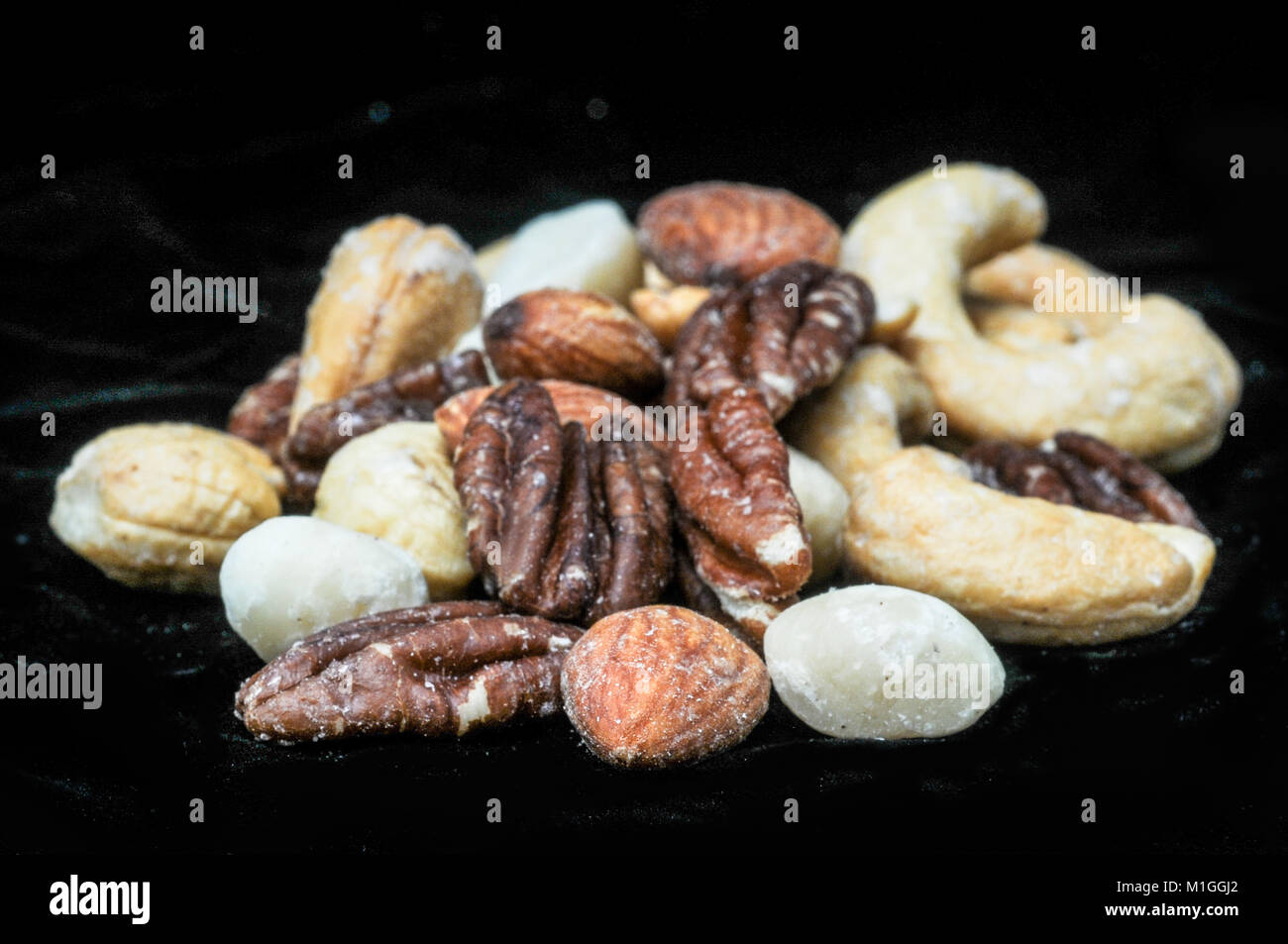 Mixed nuts on a black background Stock Photo - Alamy
