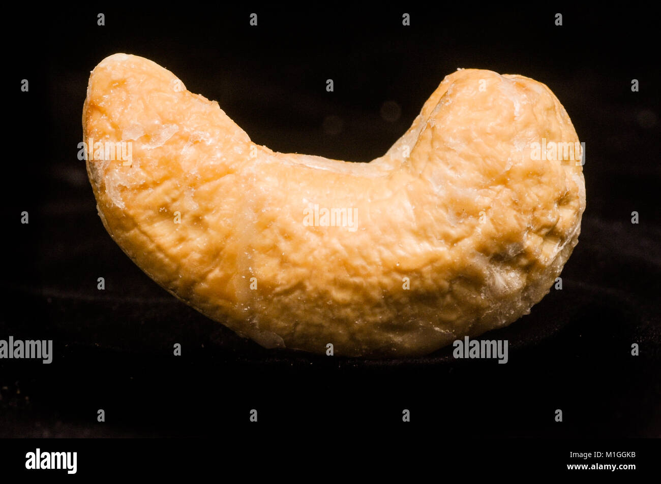 A single cashew on a black background Stock Photo - Alamy