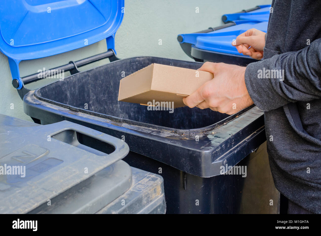 Men putting card paper box in blue garbage container for recycling ...