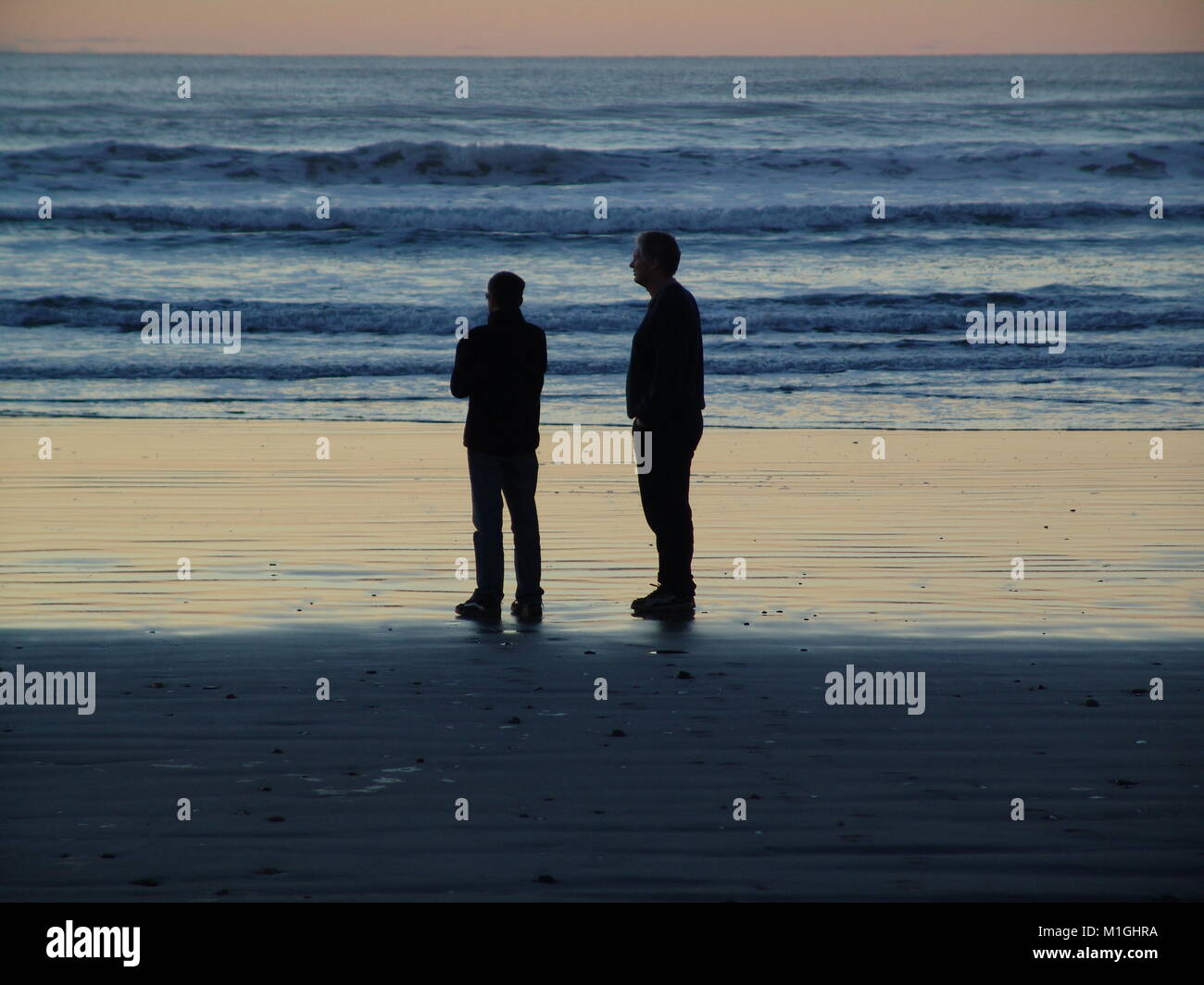 Two men at the beach during sunset. Silhouette Stock Photo - Alamy