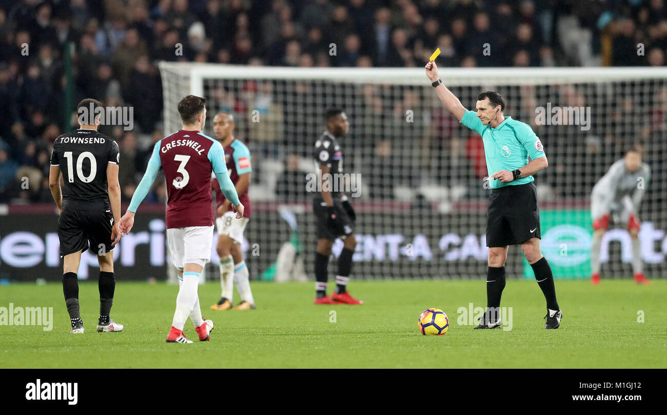 Match referee Neil Swarbrick (right) brandishes a yellow card during ...